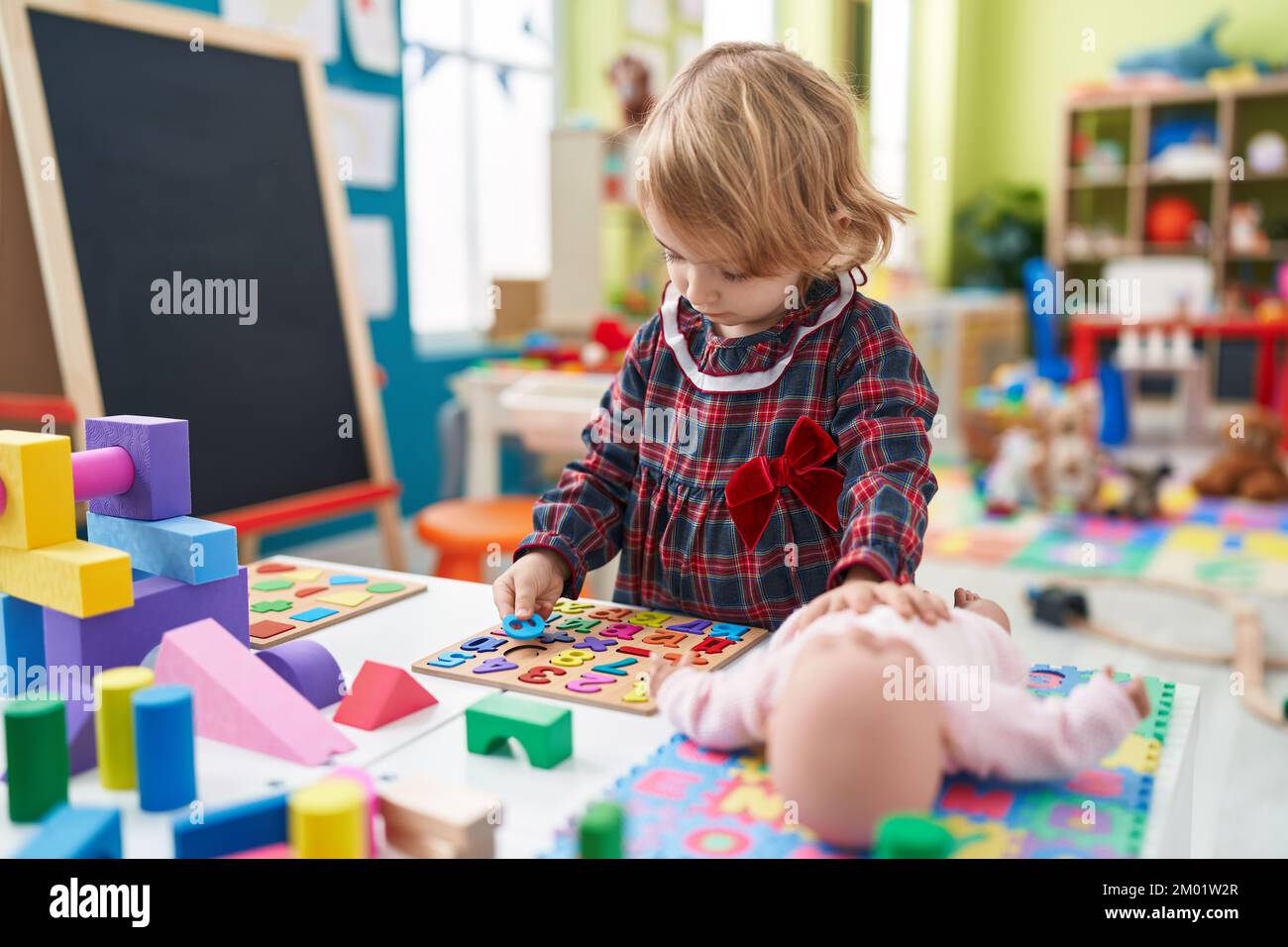 Adorable caucasian girl playing with maths game puzzle standing at ...