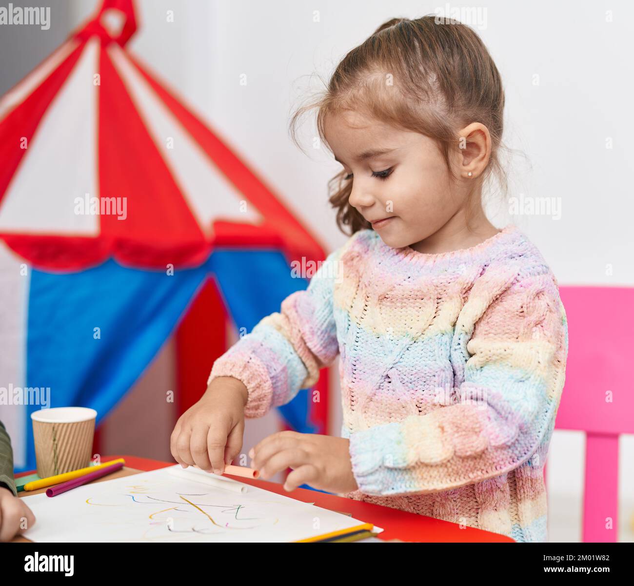 Adorable hispanic girl student drawing on paper at kindergarten Stock ...