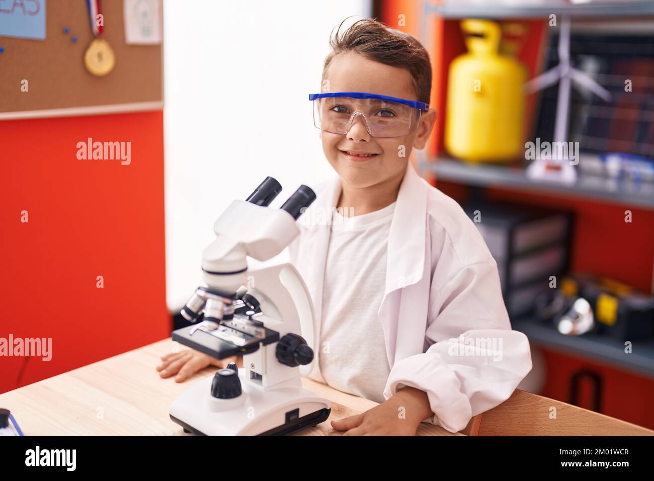 Adorable hispanic toddler student using microscope standing at ...