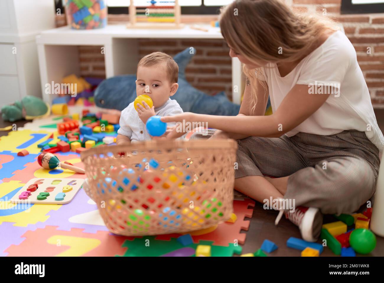 Mother and son sucking ball sitting on floor at kindergarten Stock ...