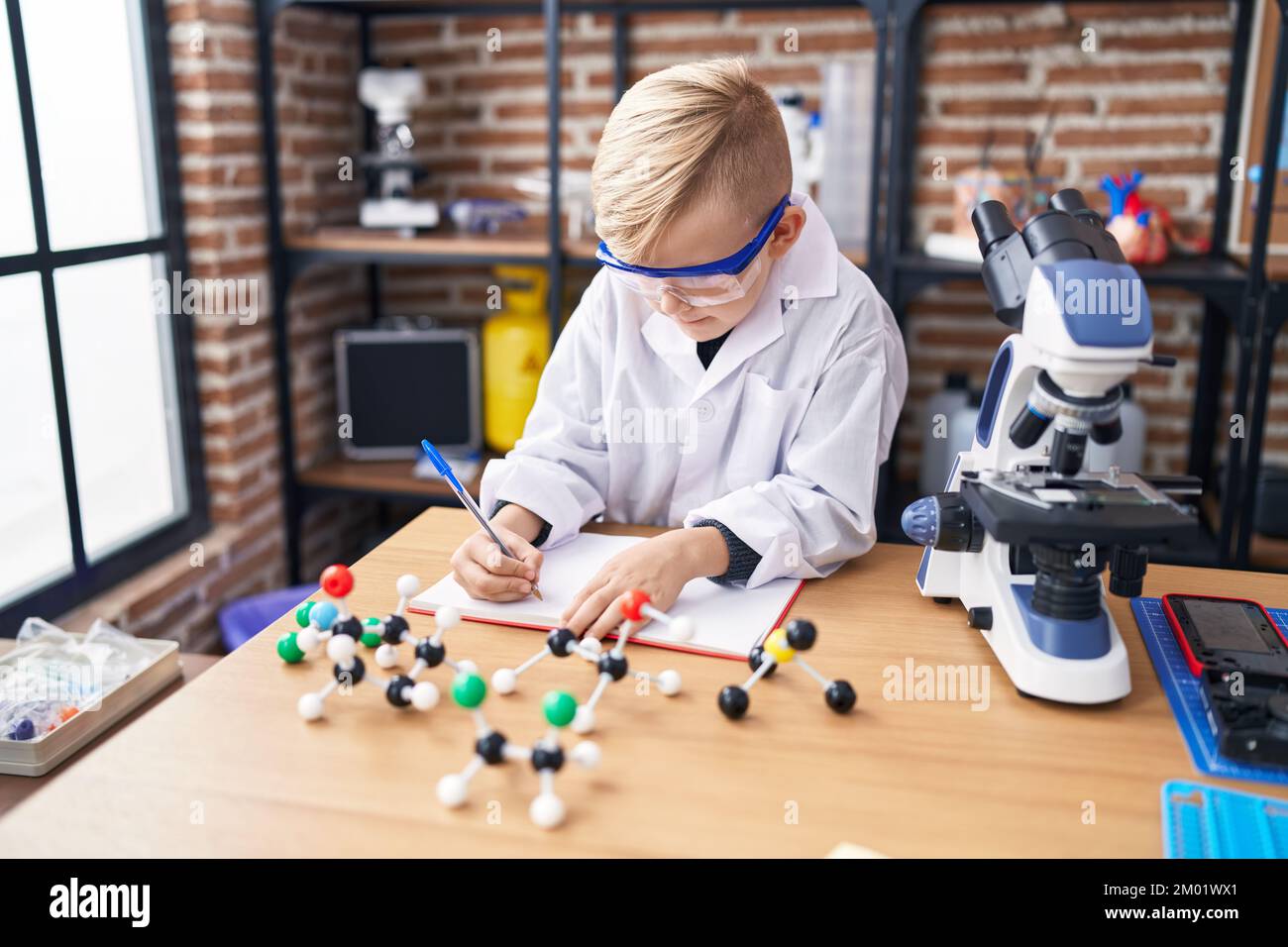 Adorable toddler student writing on notebook at classroom Stock Photo ...