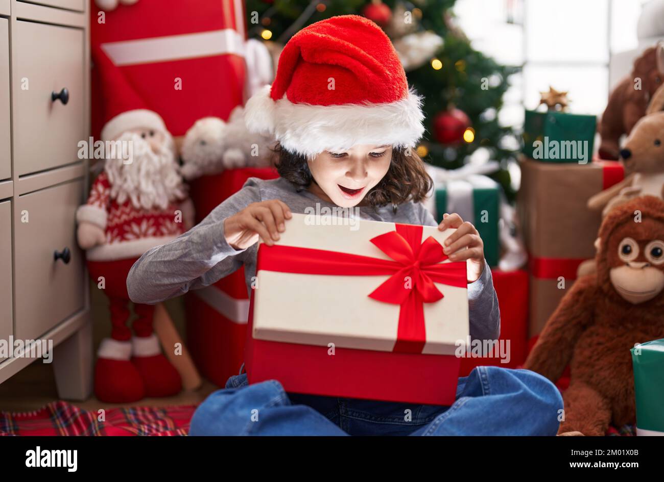 Adorable chinese girl unpacking gift with surprise expression sitting ...