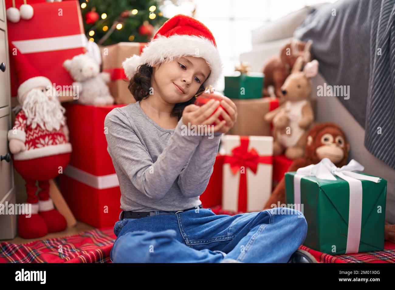 Adorable chinese girl holding ball decoration sitting on floor by ...