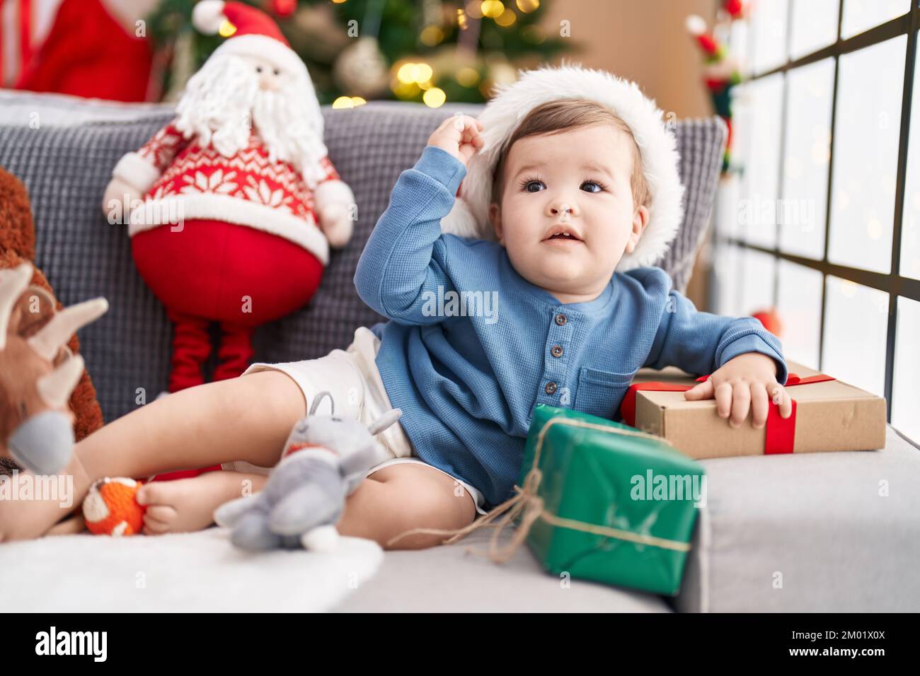 Adorable caucasian baby lying on sofa by christmas tree with relaxed ...