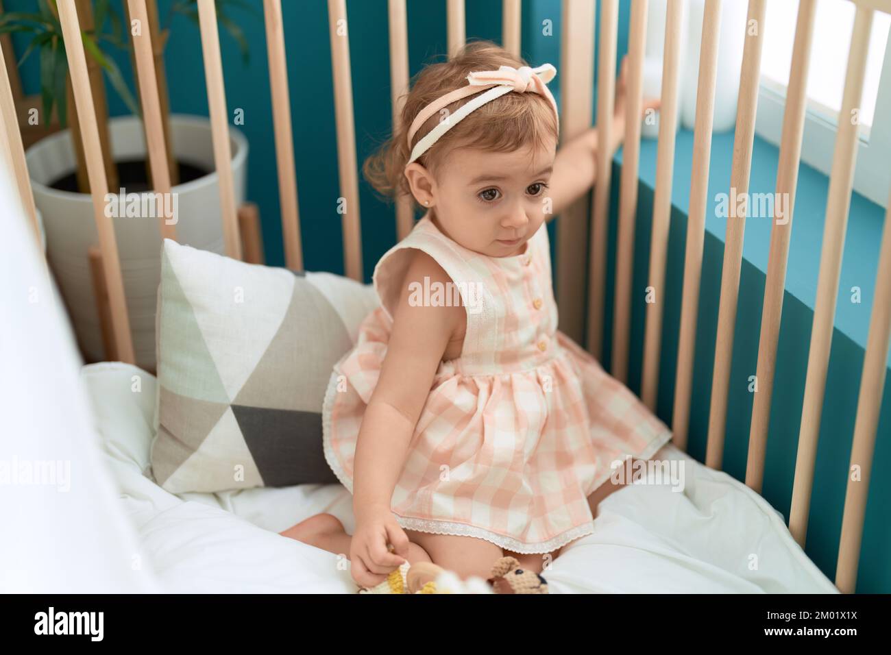 Adorable caucasian girl sitting on cradle at bedroom Stock Photo - Alamy