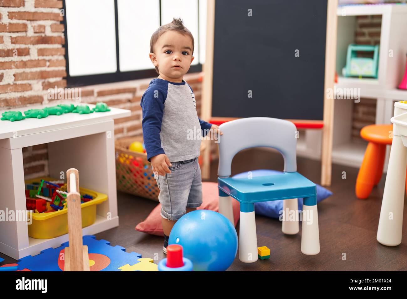 Adorable hispanic toddler standing with serious expression at ...