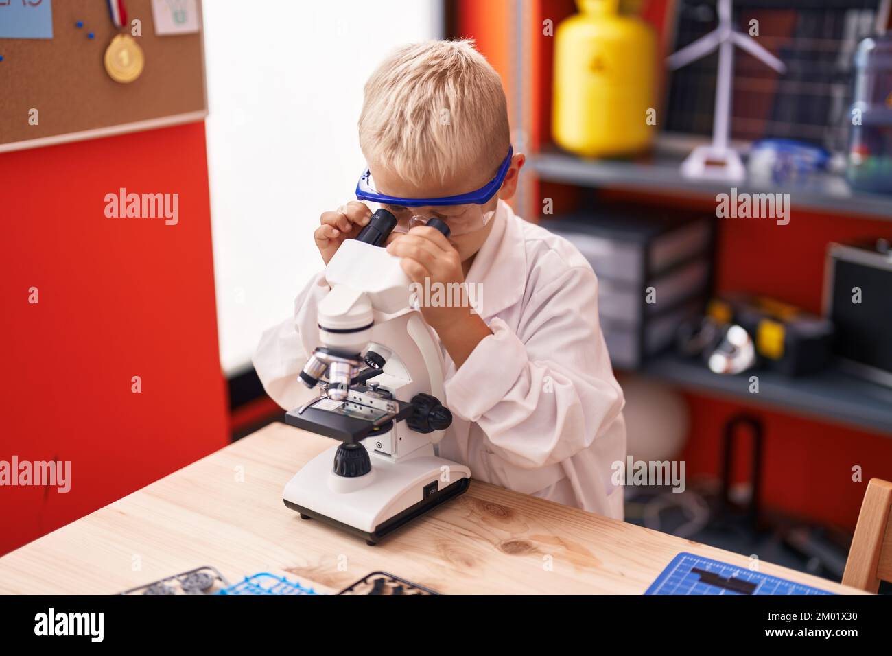 Adorable toddler student using microscope standing at classroom Stock ...