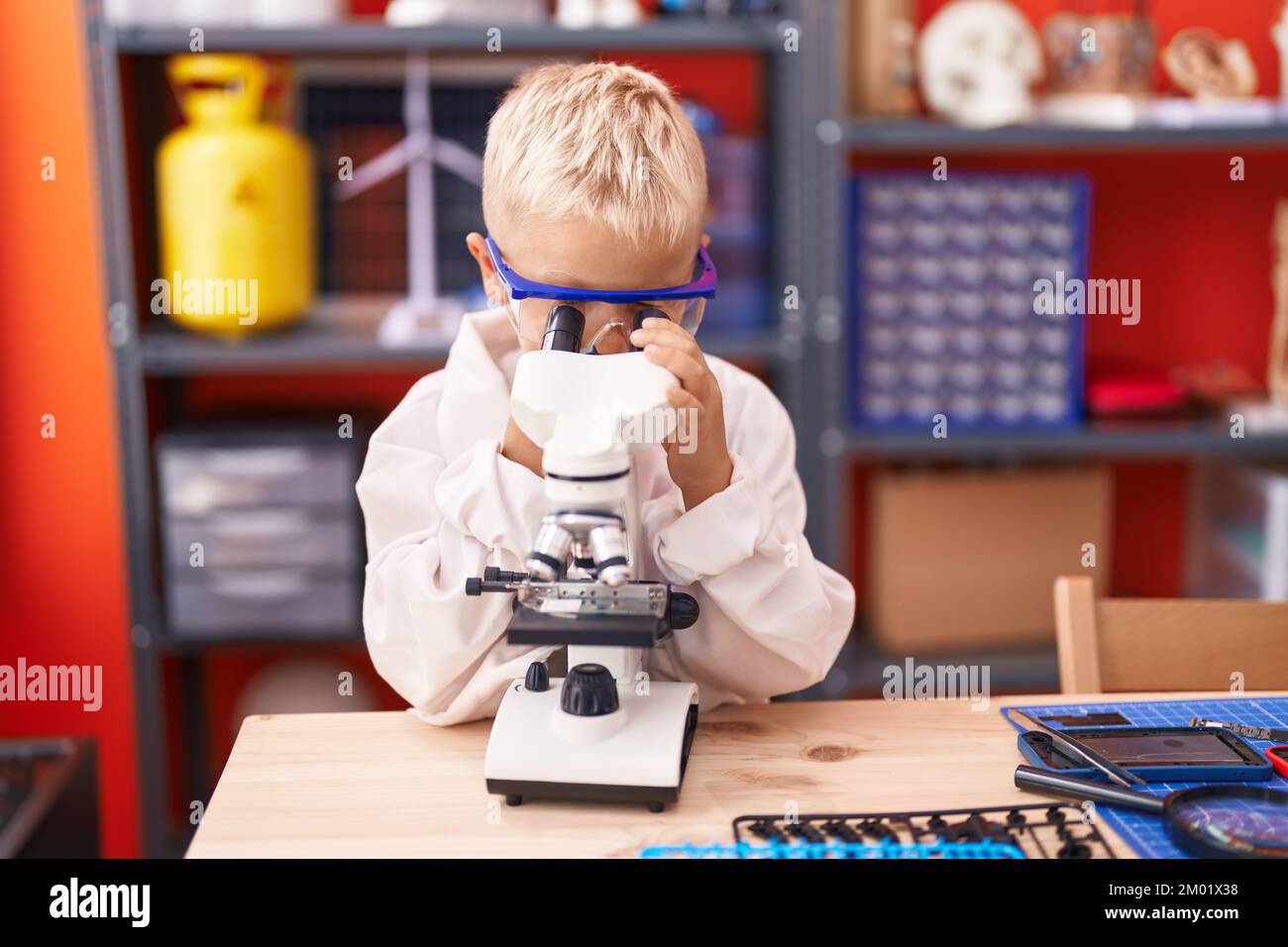 Adorable toddler student using microscope standing at classroom Stock ...