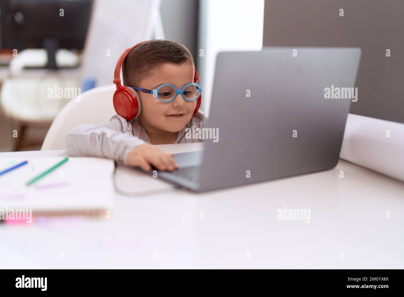 Adorable hispanic toddler student using laptop and headphones studying ...