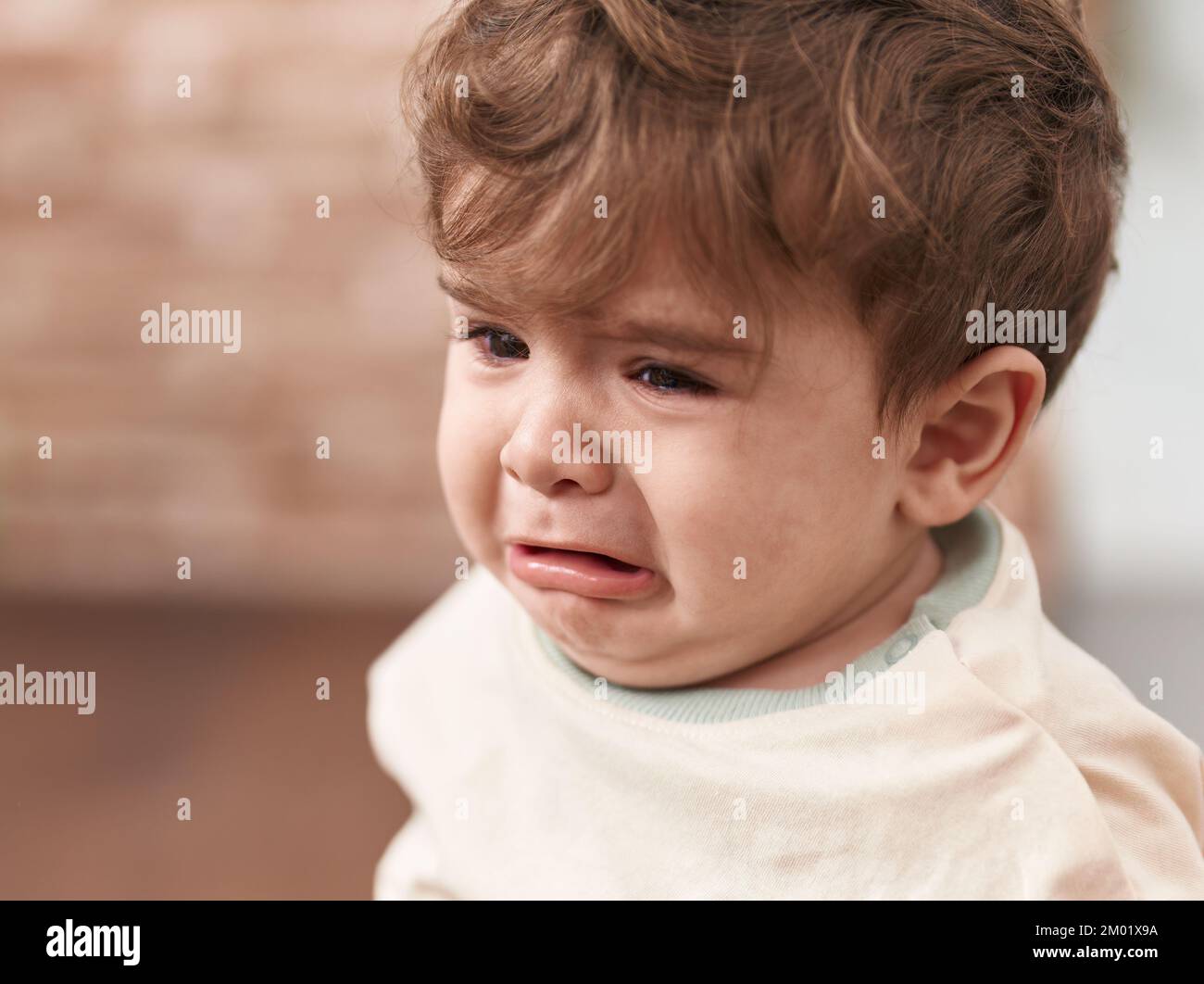 Adorable hispanic toddler sitting on floor crying at home Stock Photo ...