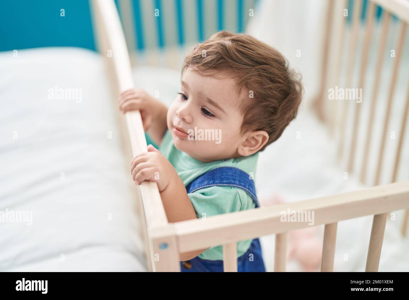 Adorable hispanic toddler smiling confident standing on cradle at ...