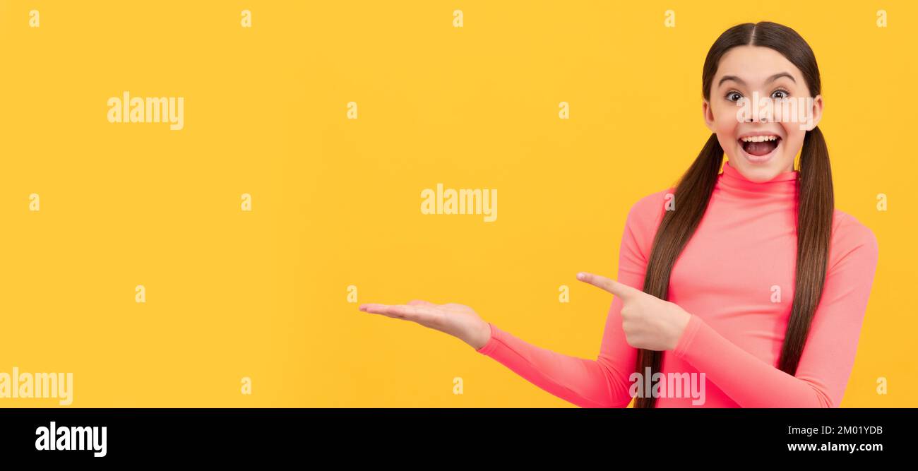 amazed kid pointing finger on copy space on yellow background, shopping ...