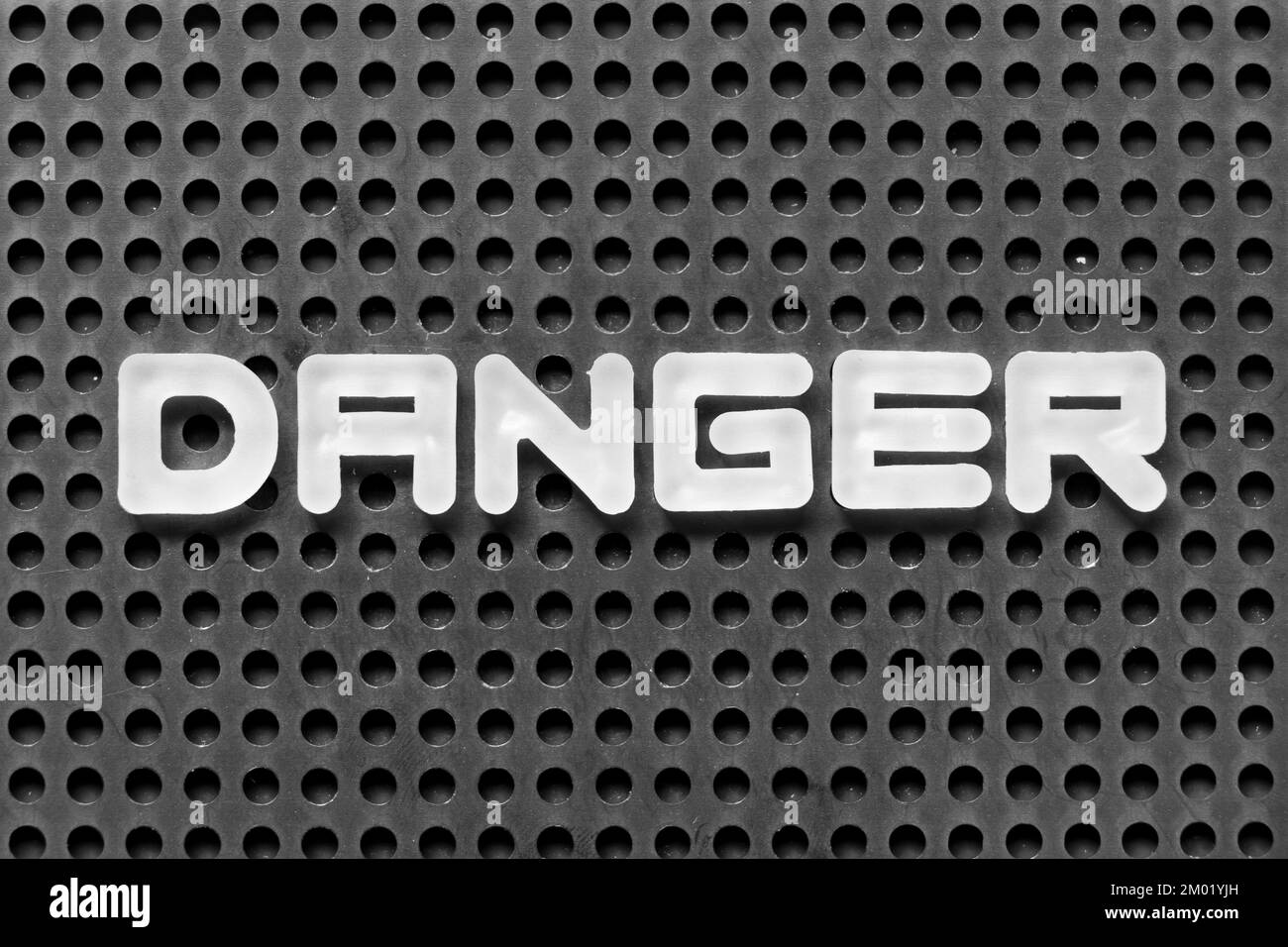White alphabet letter in word danger on black pegboard background Stock ...