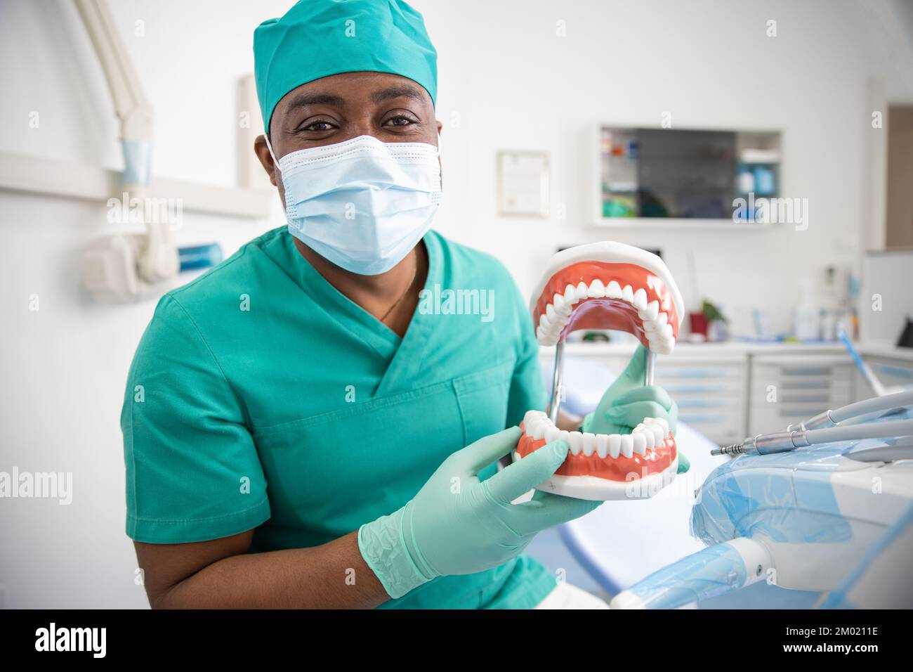An african dentist holding a dentition teeth model in his hand, dental ...