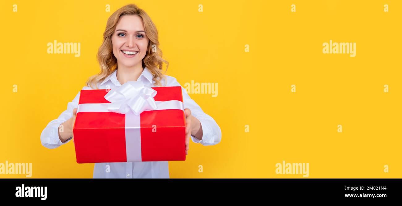 cheerful woman with big present box on yellow background. Woman ...