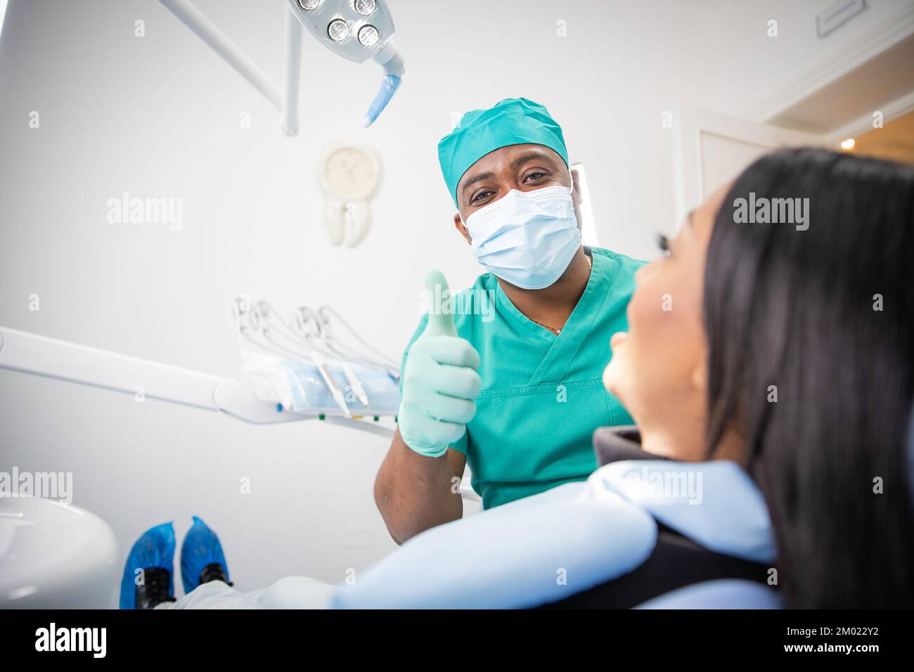 A satisfied dentist during a visit with a patient makes the thumbs up ...