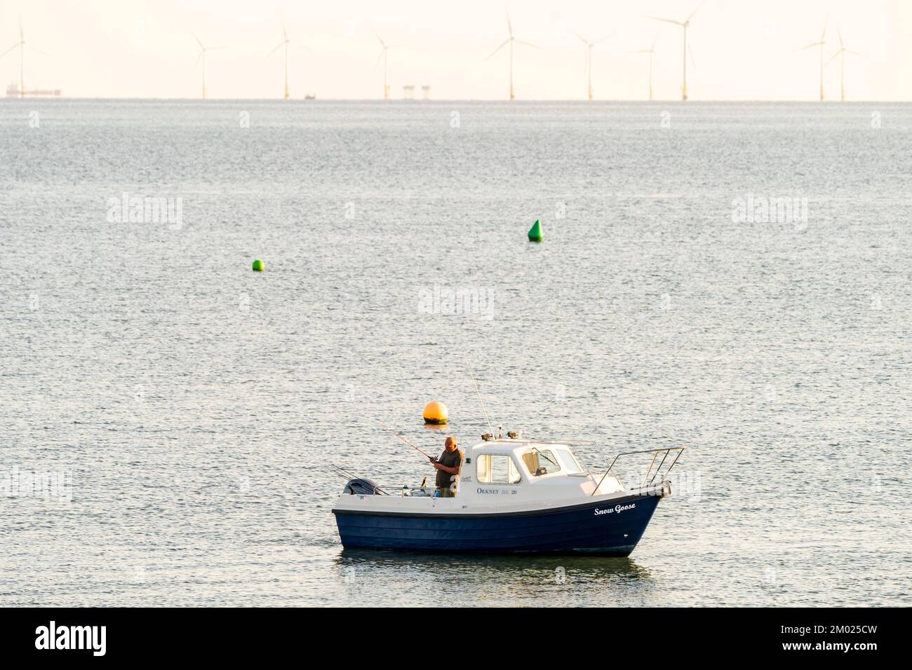 Man aboard a small boat, cabin cruiser, in the early morning, fishing ...