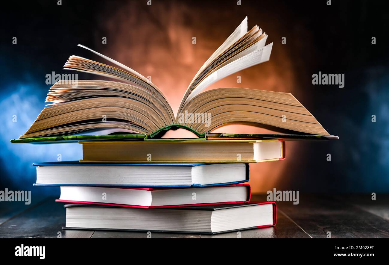 A composition with an open book lying on a stack of other books Stock ...