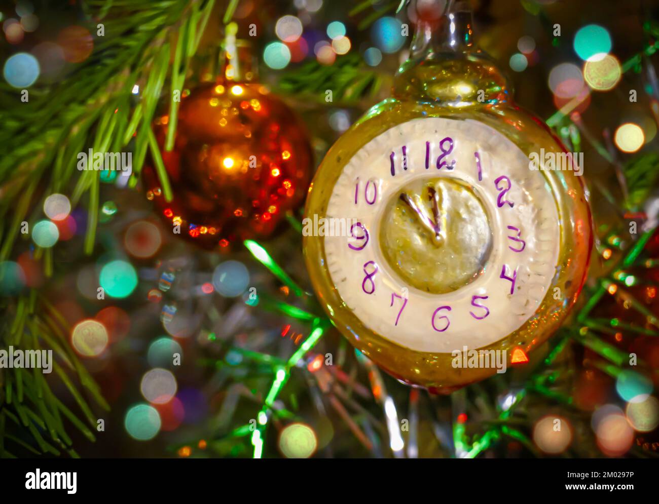 Christmas toy in the form of a clock on a festive tree shows the time ...