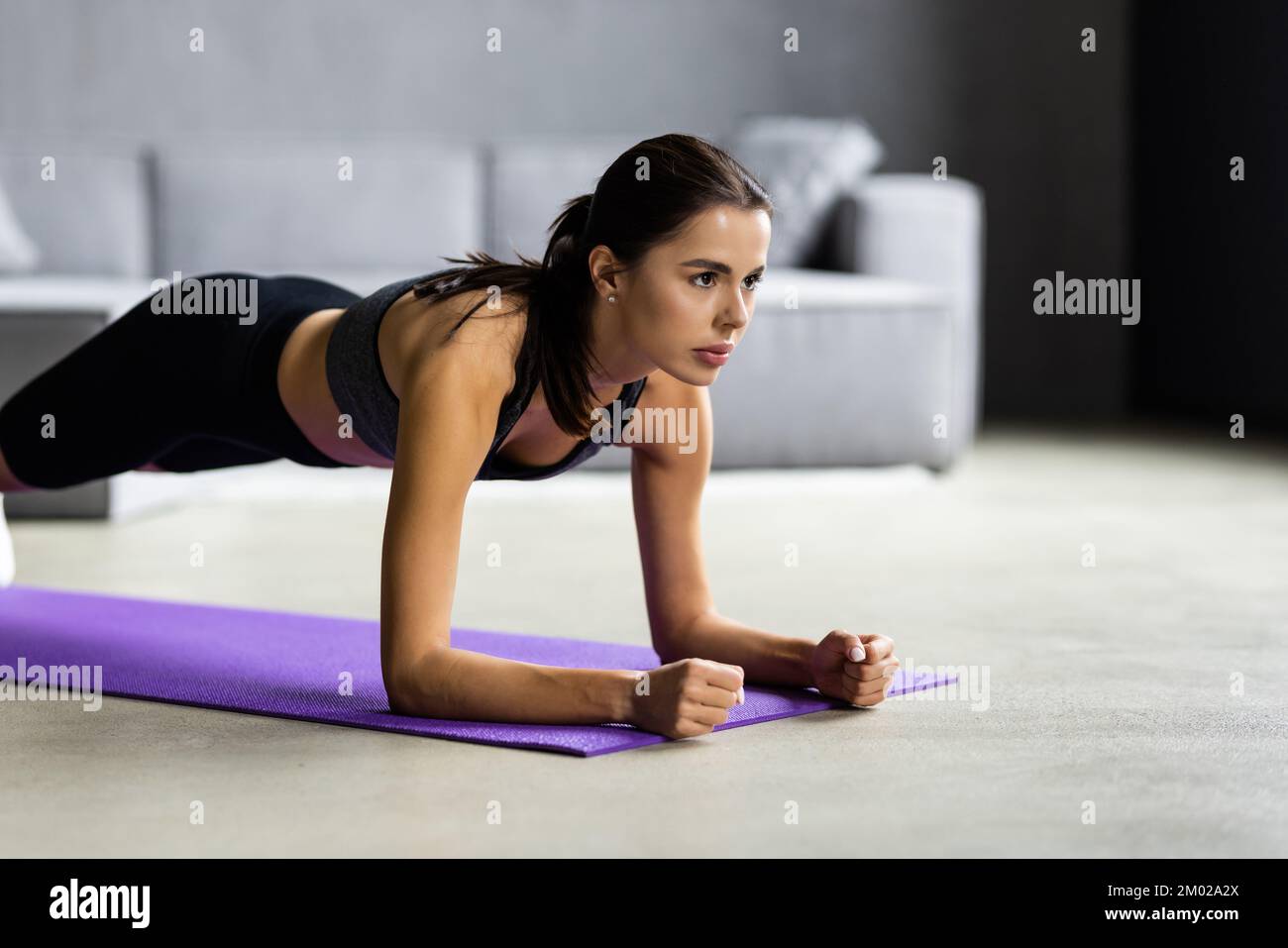 Slim fitnes young girl with ponytail doing planking exercise indoors at ...