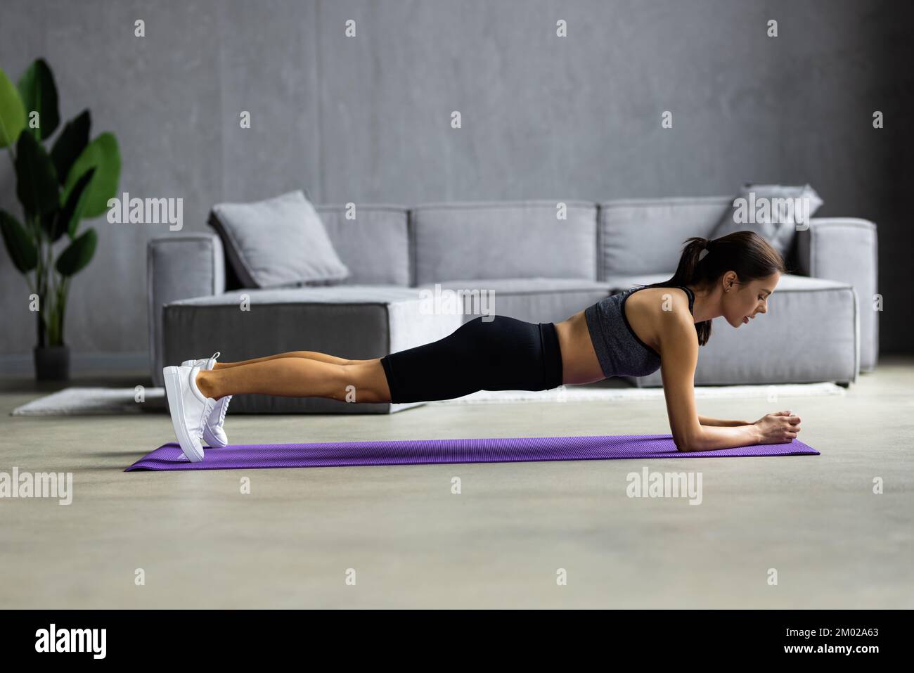 Slim fitnes young girl with ponytail doing planking exercise indoors at ...