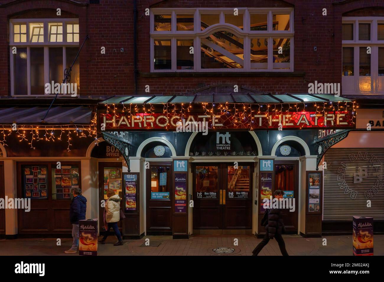 People walk by the entrance to Harrogate Theatre with an illuminated ...