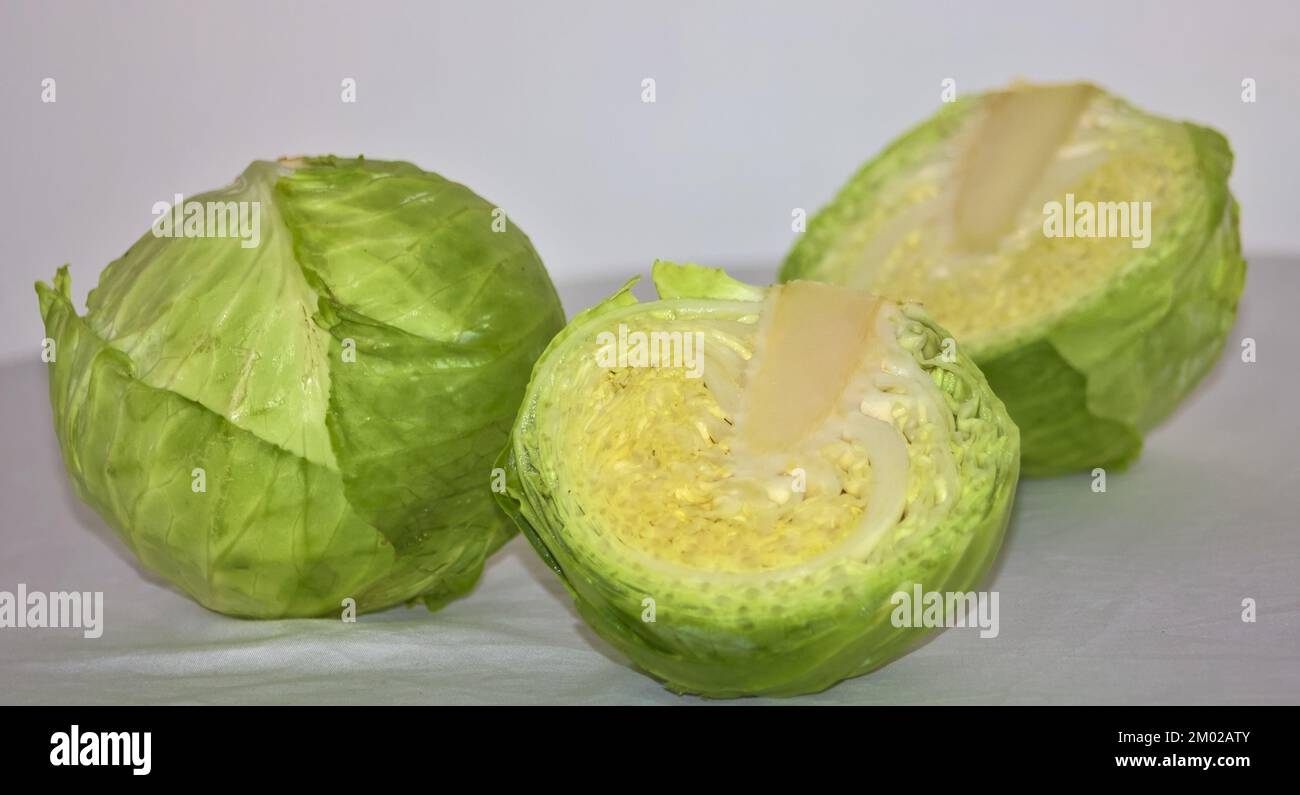 two cabbages on a white background, one of them whole and the other ...