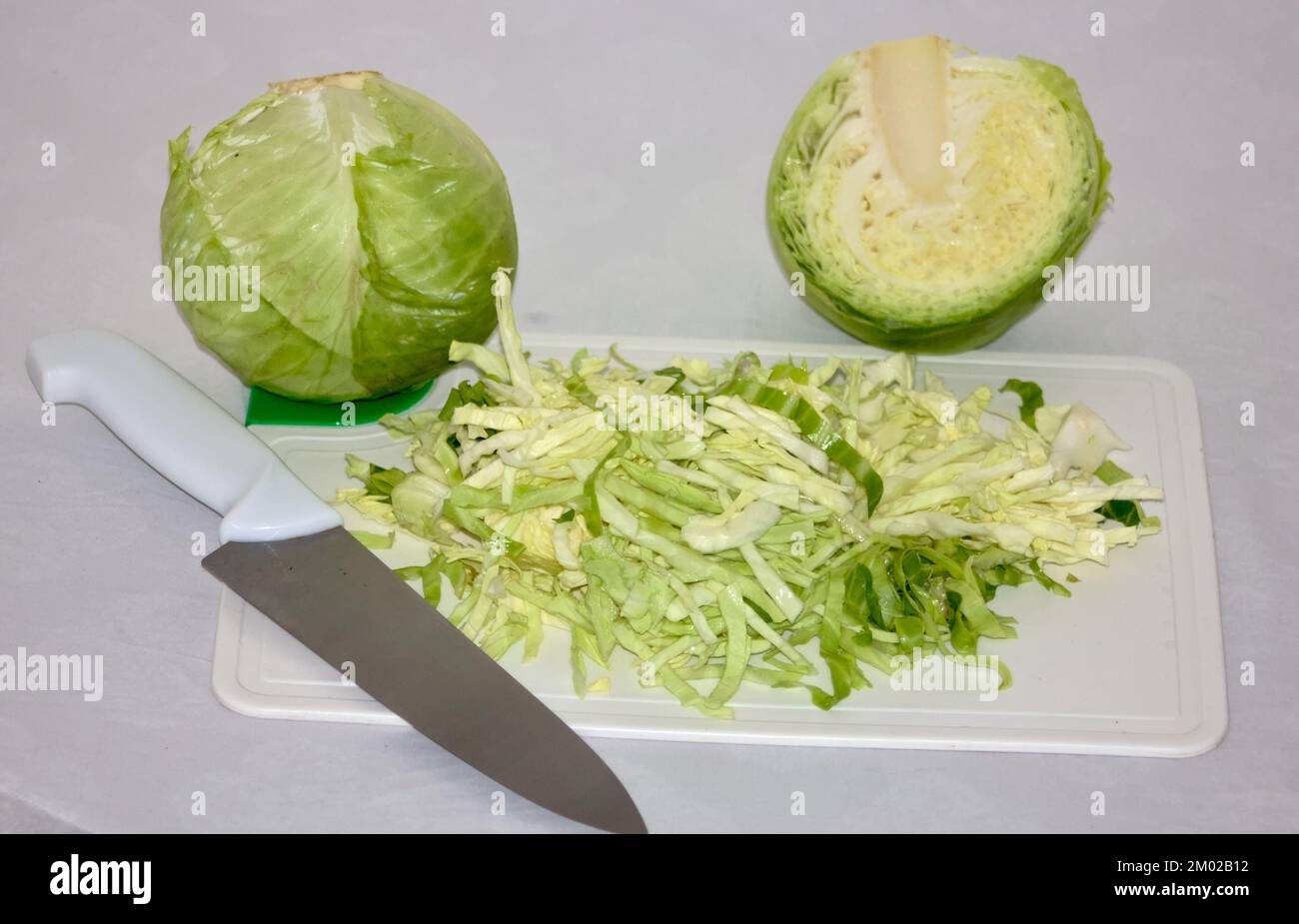 several cabbages, one finely chopped on a cutting table, another cut in ...