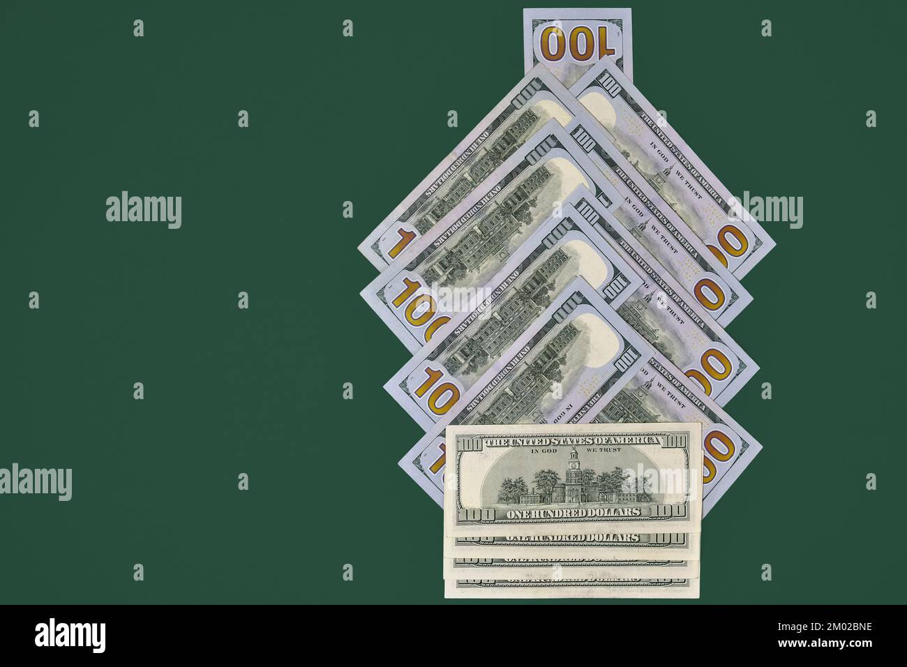 Christmas tree made from hundred dollar bills on green background. Copy ...