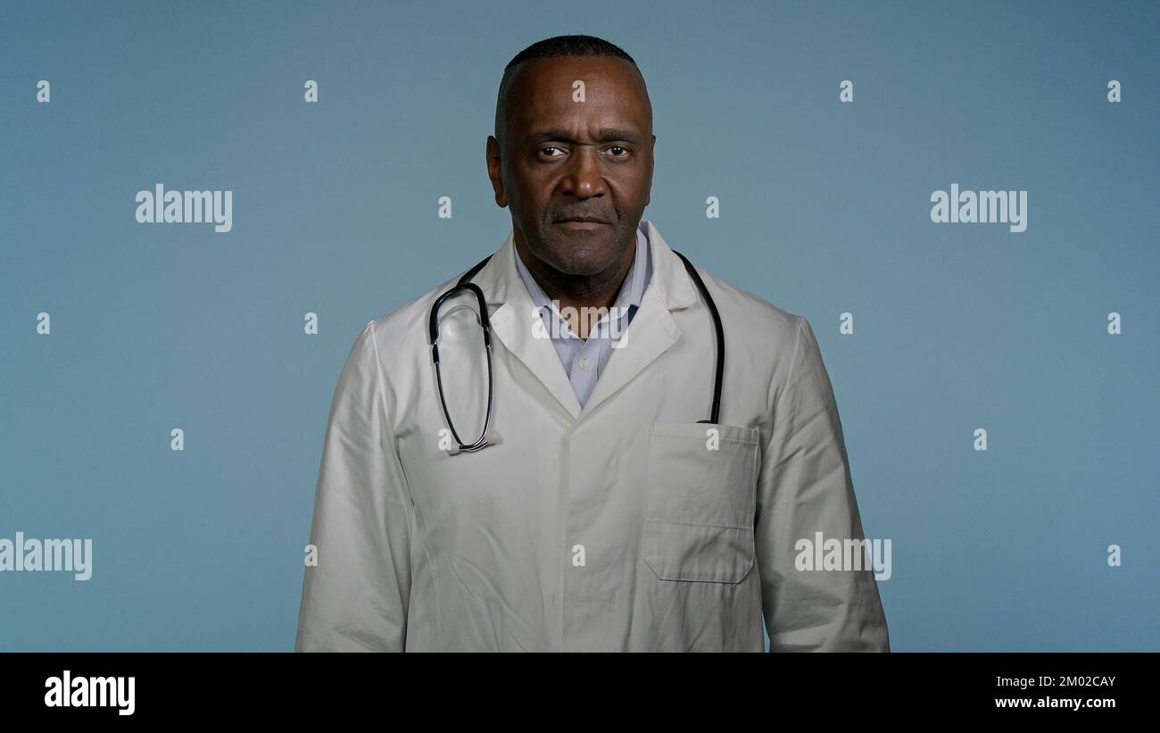 Mature confident happy doctor standing in gray background studio with ...