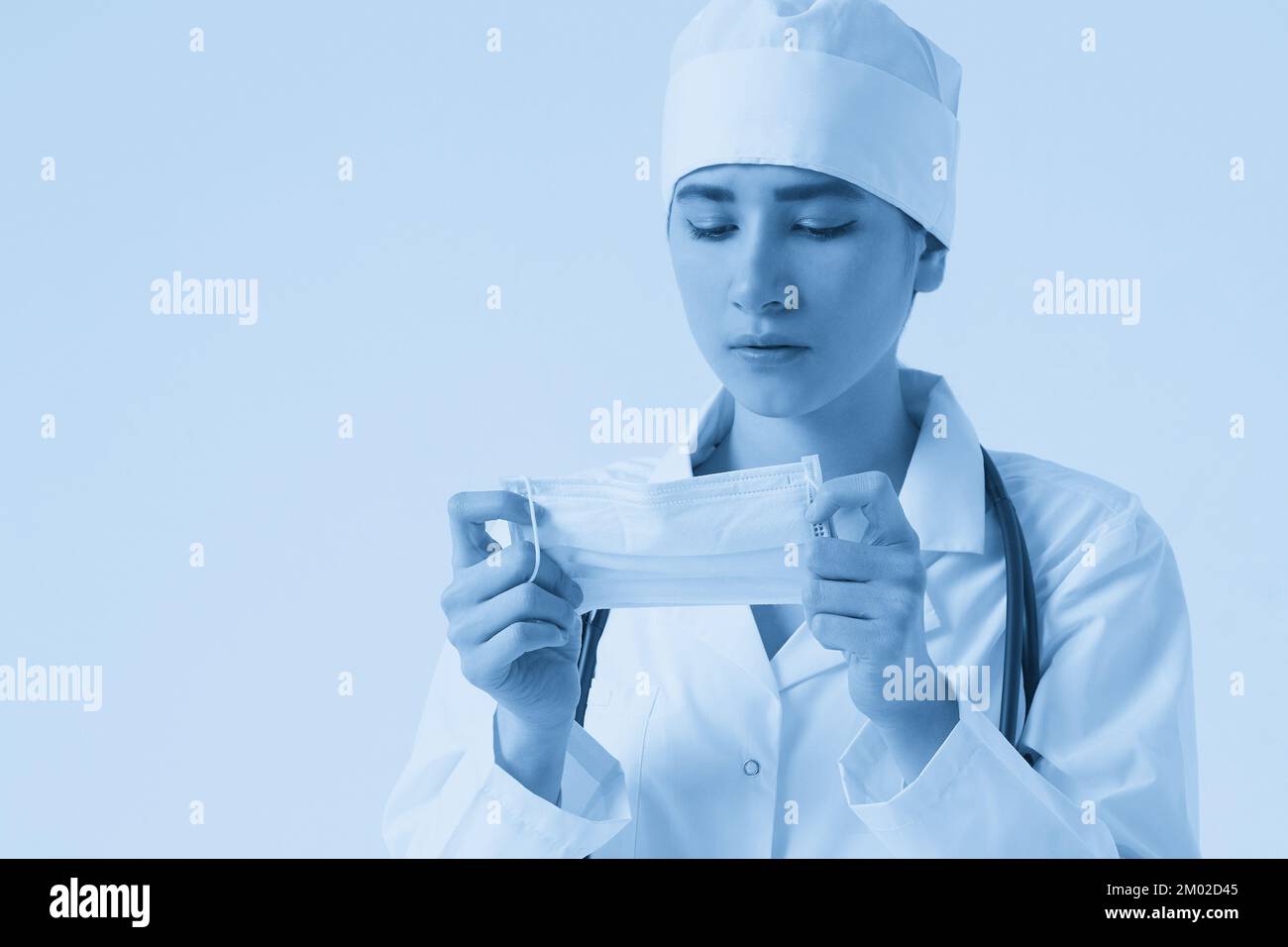Portrait of young female doctor putting on protective medical face mask ...