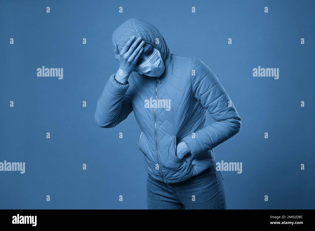 woman wearing hood in a protective face mask and coat over blue ...