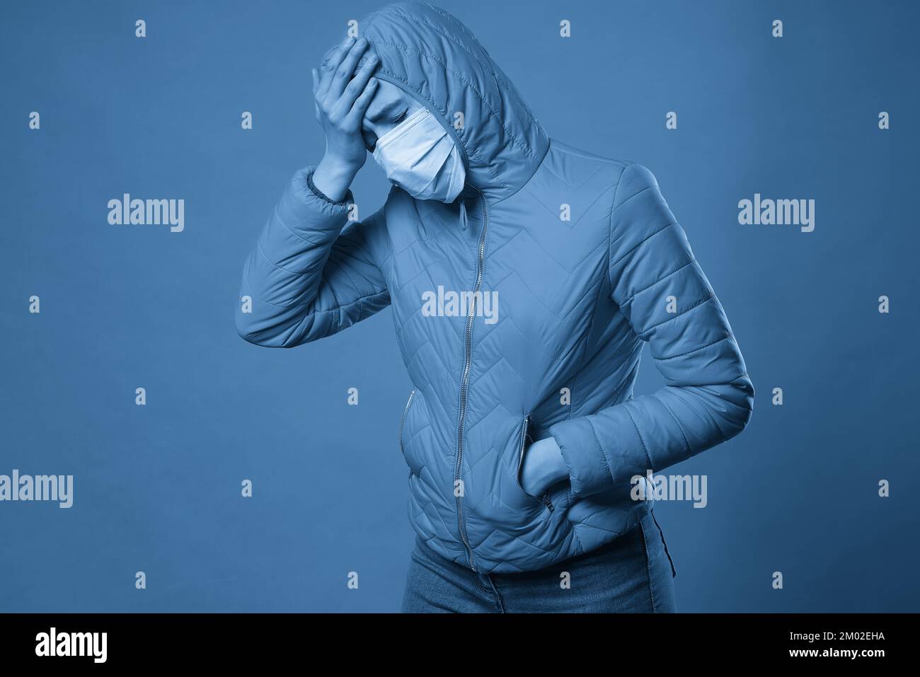 woman wearing hood in a protective face mask and coat over blue ...
