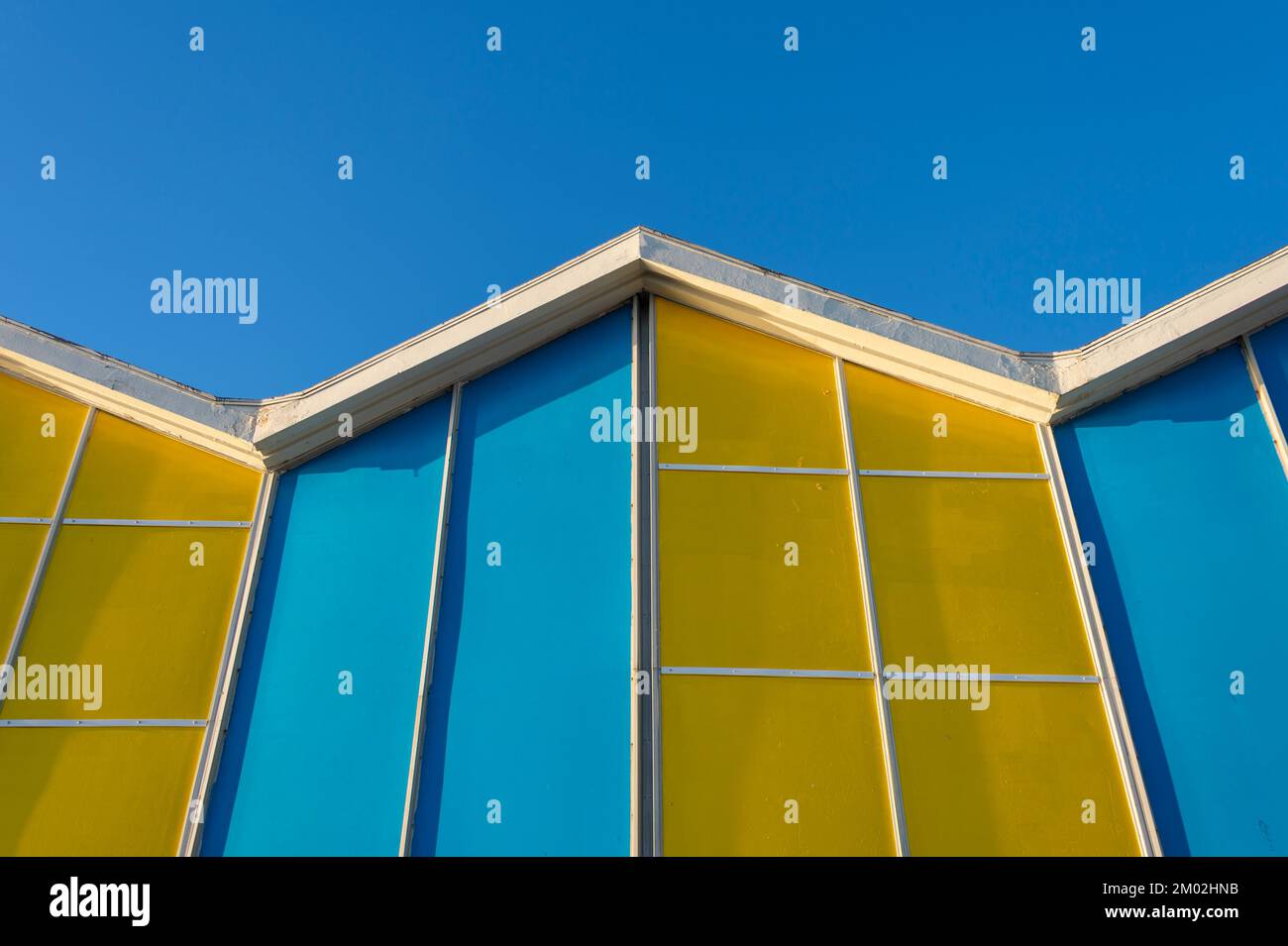 Side of a blue and yellow building against a blue sky. Colourful ...