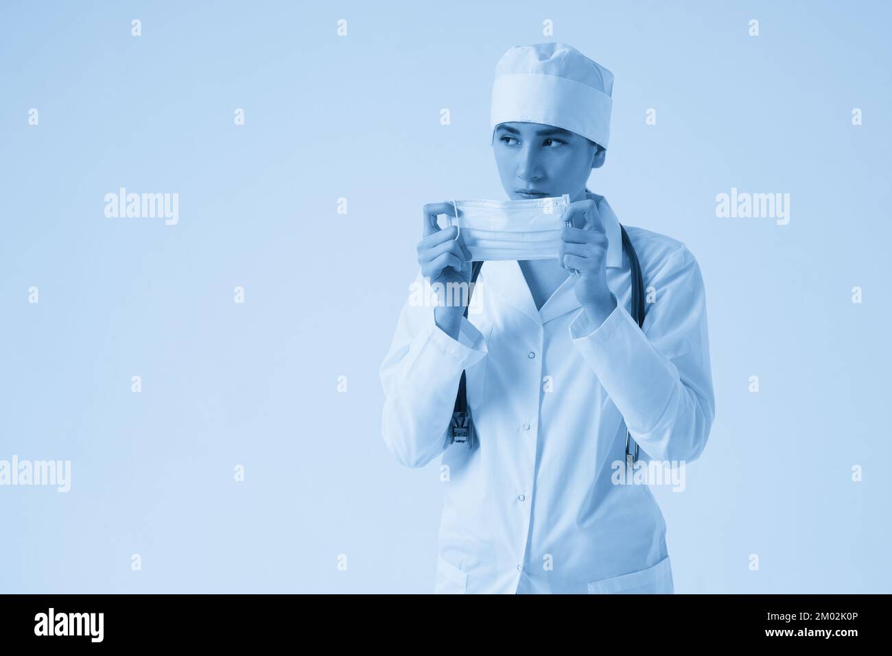 Portrait of young female doctor putting on protective medical face mask ...