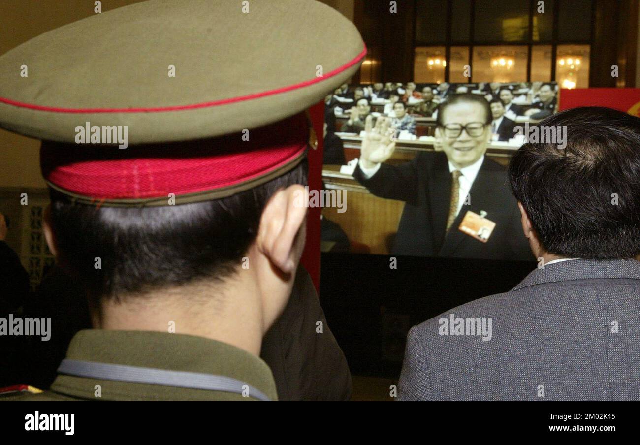 A PLA soldier watches as Jiang Zemin waves to delegates after being ...