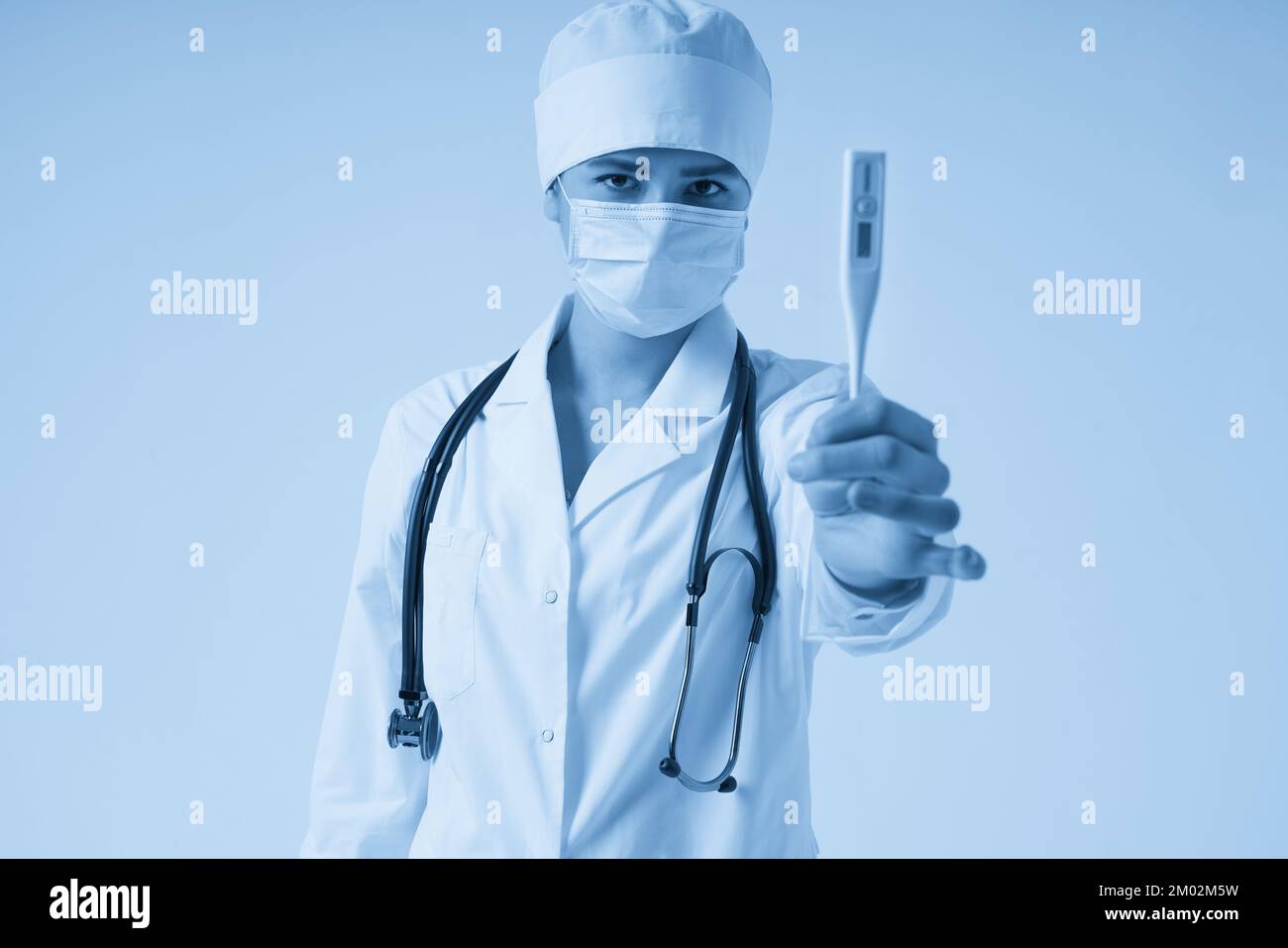 Young female doctor showing thermometer over white background, studio ...