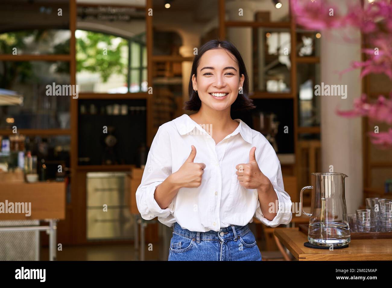 Happy asian woman shows thumbs up, approves, likes smth good, stands ...
