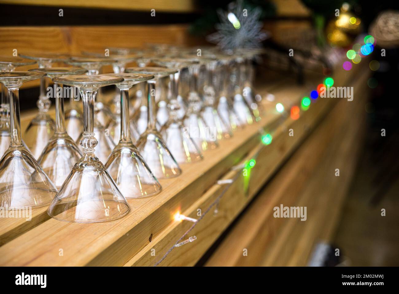 clean martini glasses are upside down on the wooden shelf of the bar ...