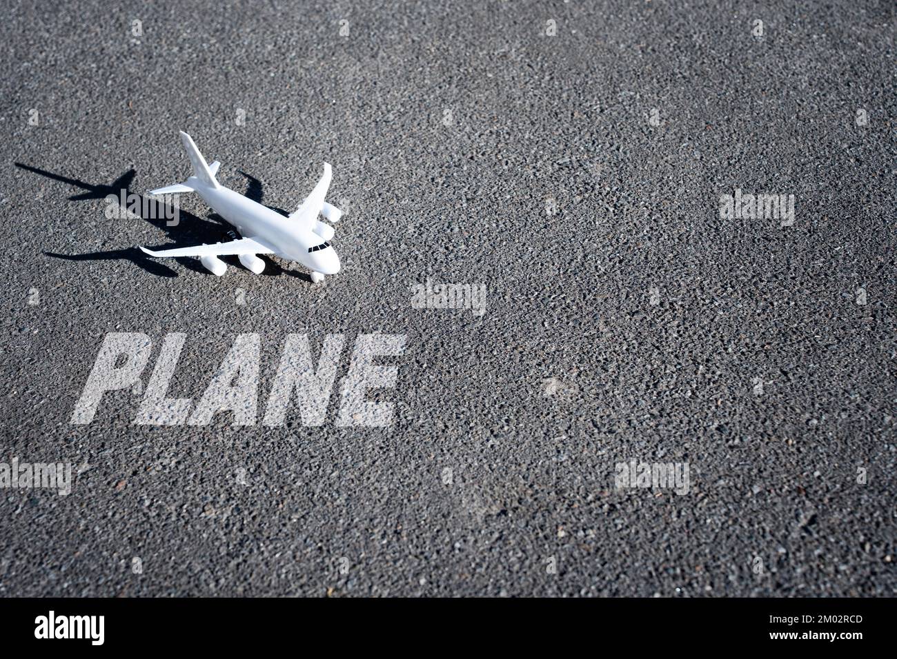 Model aircraft and word PLANE painted on the runway with copy space ...