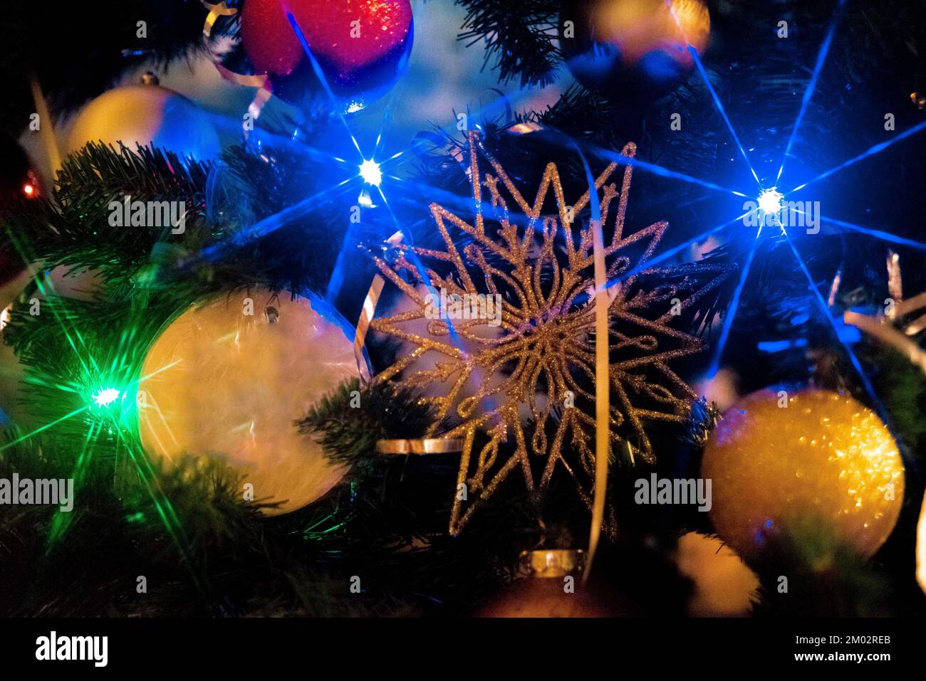 Christmas lights in star shape on the branches of a pine tree, balls on ...