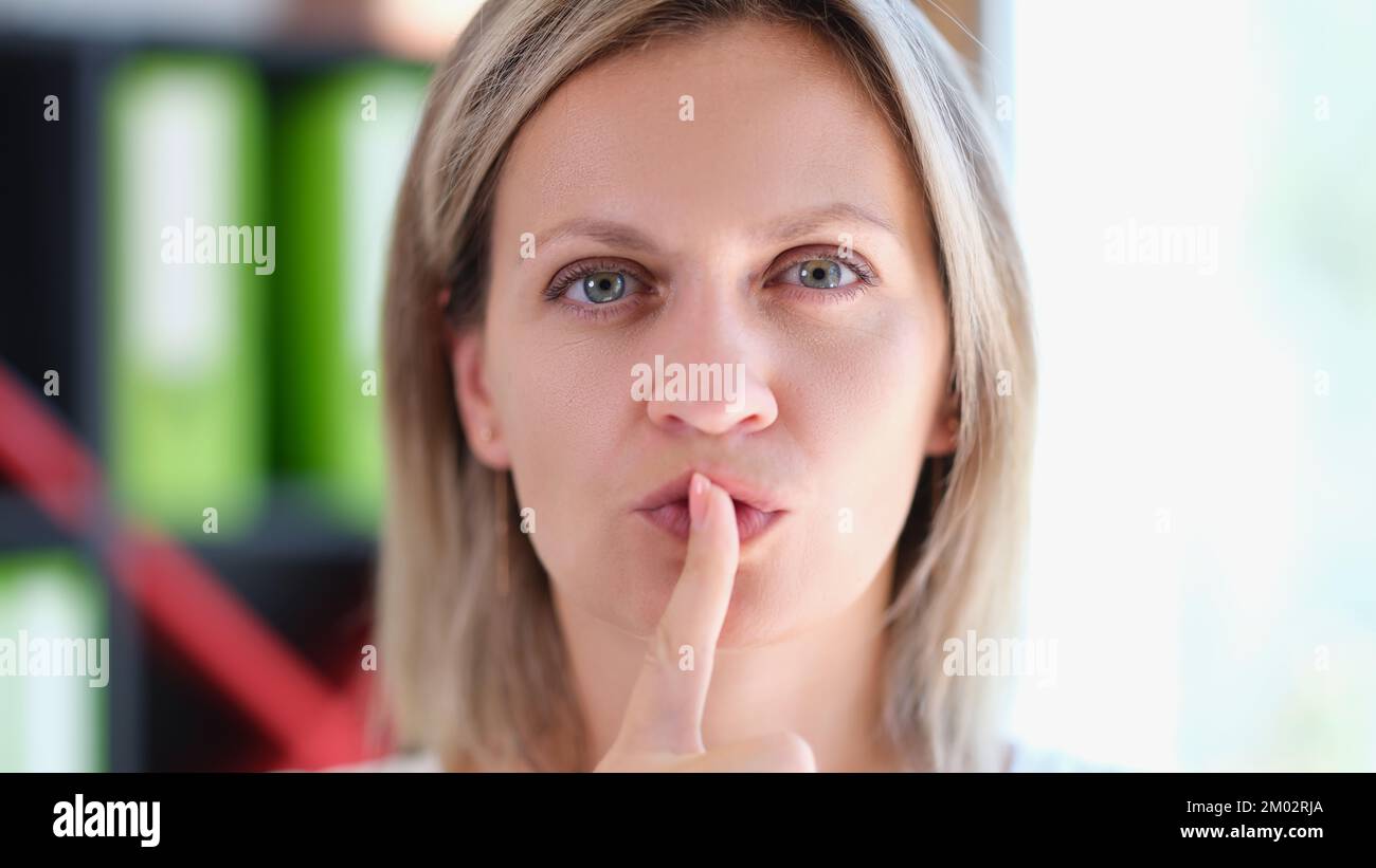 Woman holding finger on her lips gesturing silent Stock Photo - Alamy