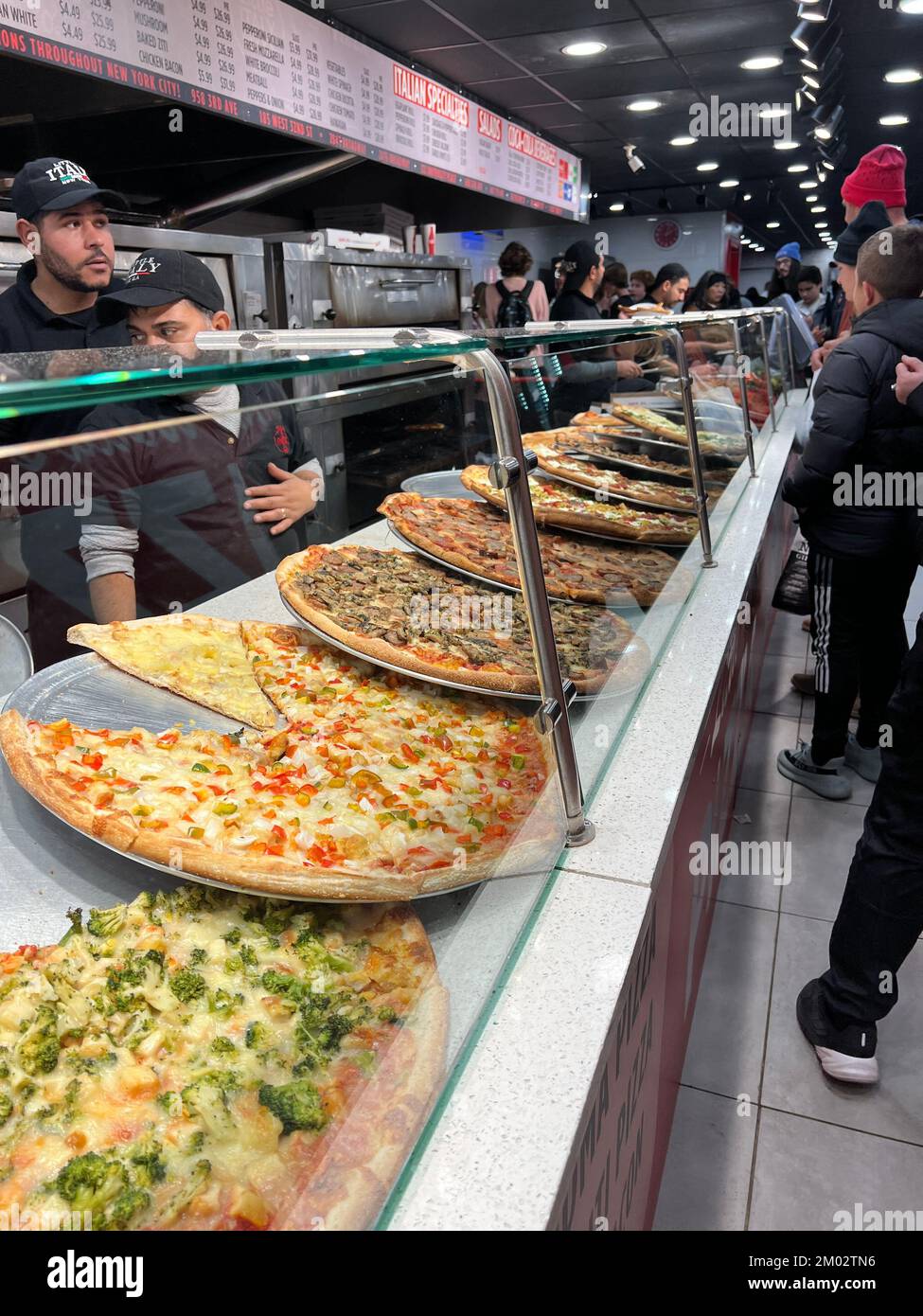 Pizzas with a variety of toppings, at a busy midtown Pizza parlor in ...