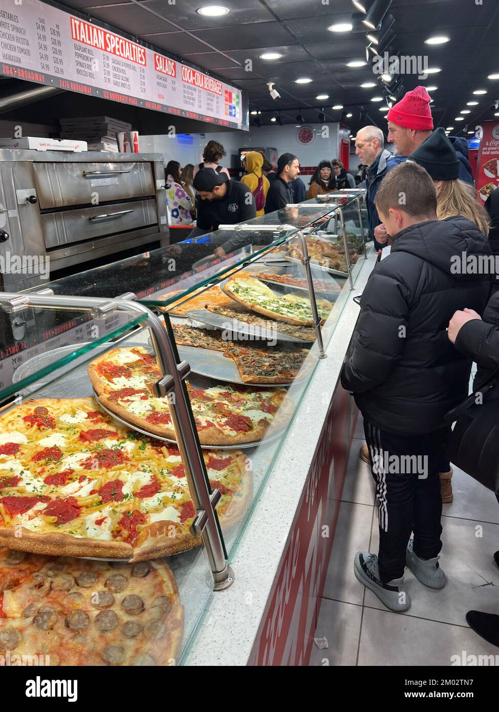 Pizzas with a variety of toppings, at a busy midtown Pizza parlor in ...