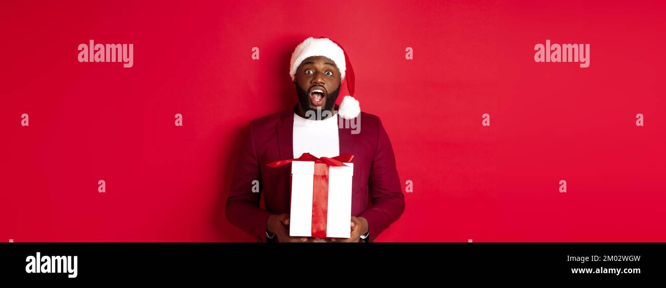 Christmas, New Year and shopping concept. Excited Black man receiving ...