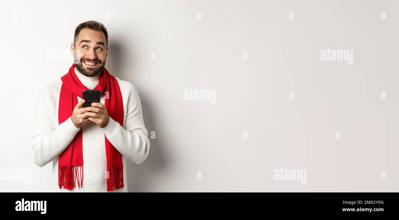Man thinking while texting message on mobile phone, smiling and ...