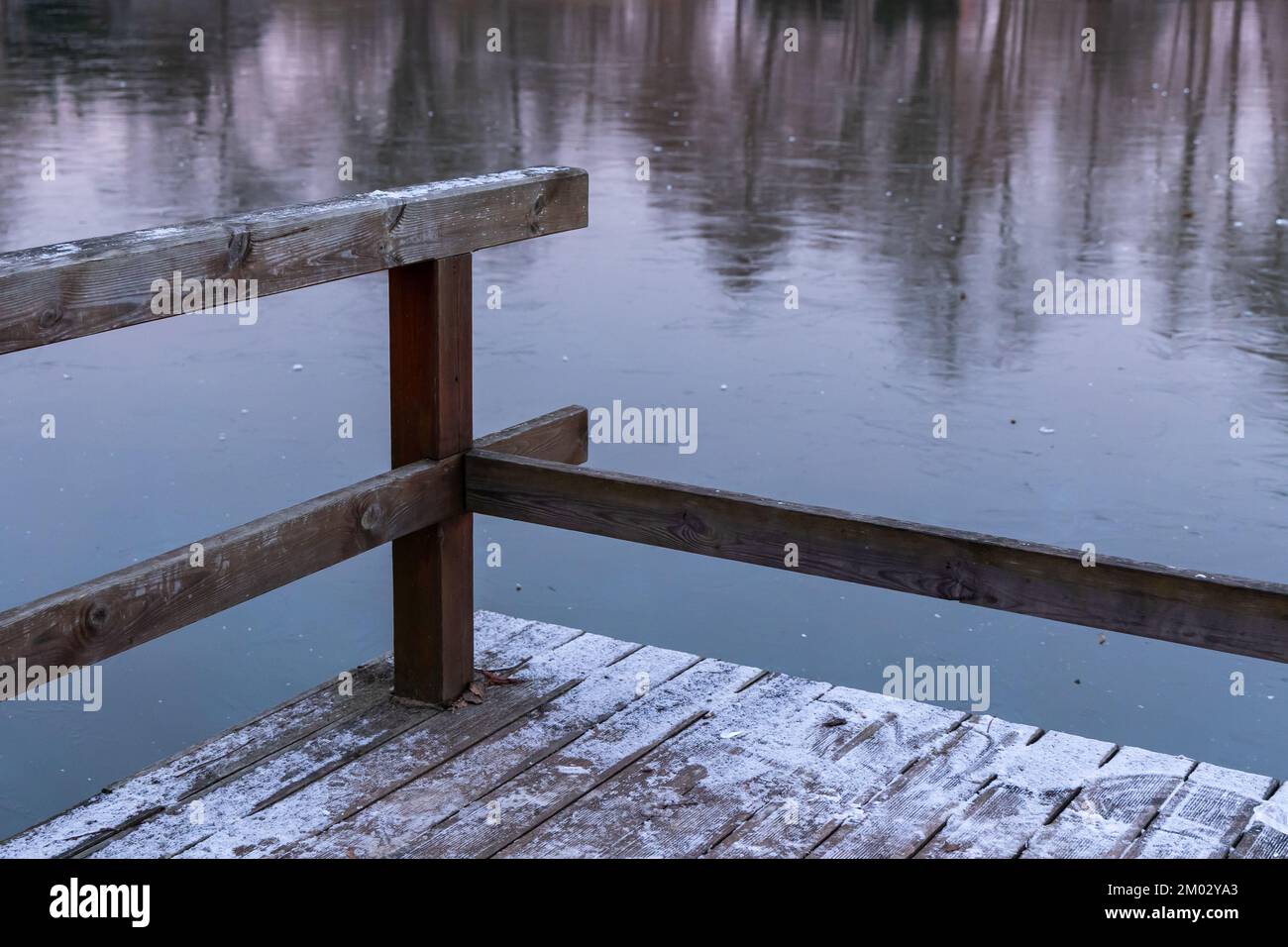 A wooden pier on a lake covered with a thin layer of snow. Danger of ...