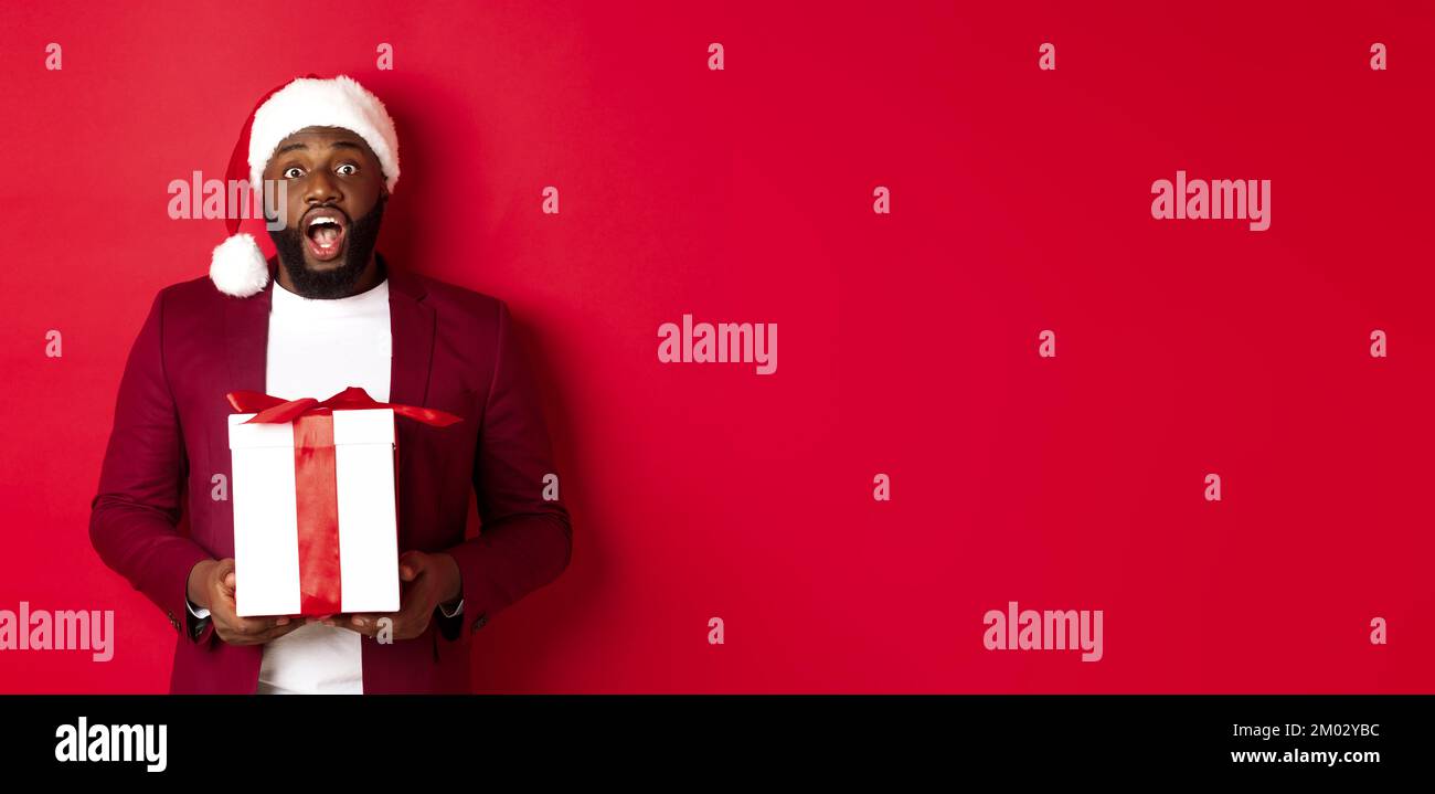 Christmas, New Year and shopping concept. Excited Black man receiving ...