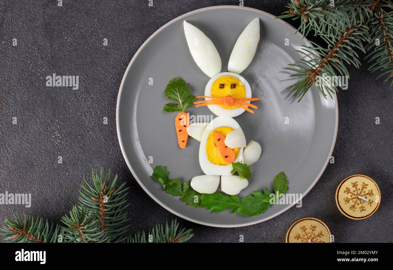 Funny rabbit made from boiled eggs, peeled carrots and arugula on gray ...