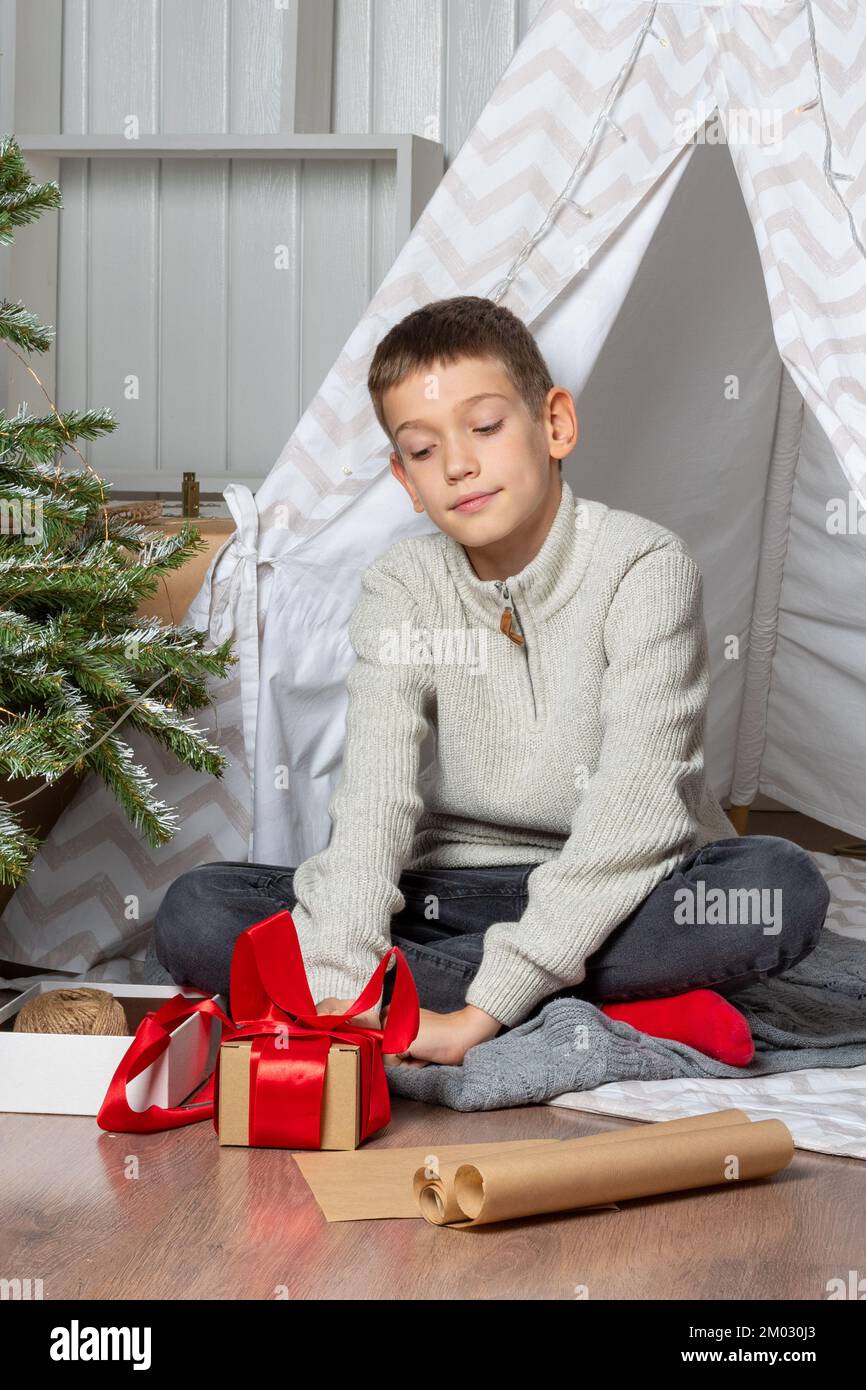 Gift wrapping. A teen child wraps Christmas gifts surprises in kraft ...